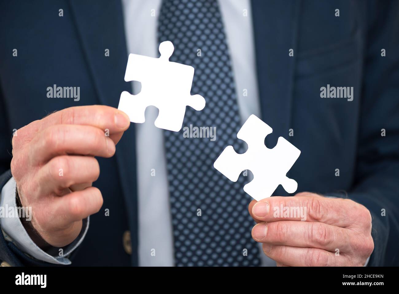 Businessman joining two puzzle pieces, teamwork concept Stock Photo - Alamy