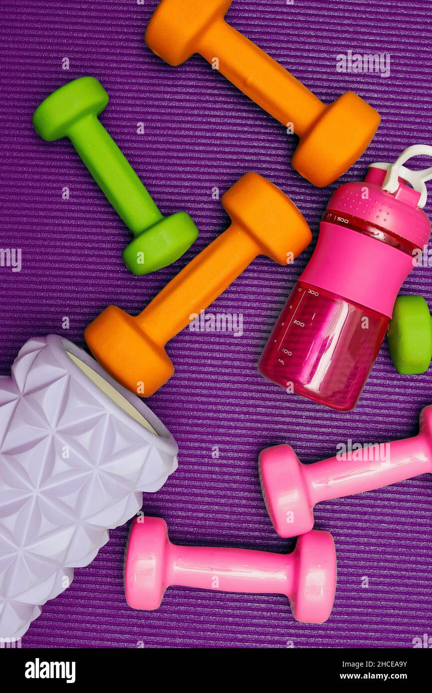 Vertical backdrop with scattered fitness equipment, dumbbell, roller on ...