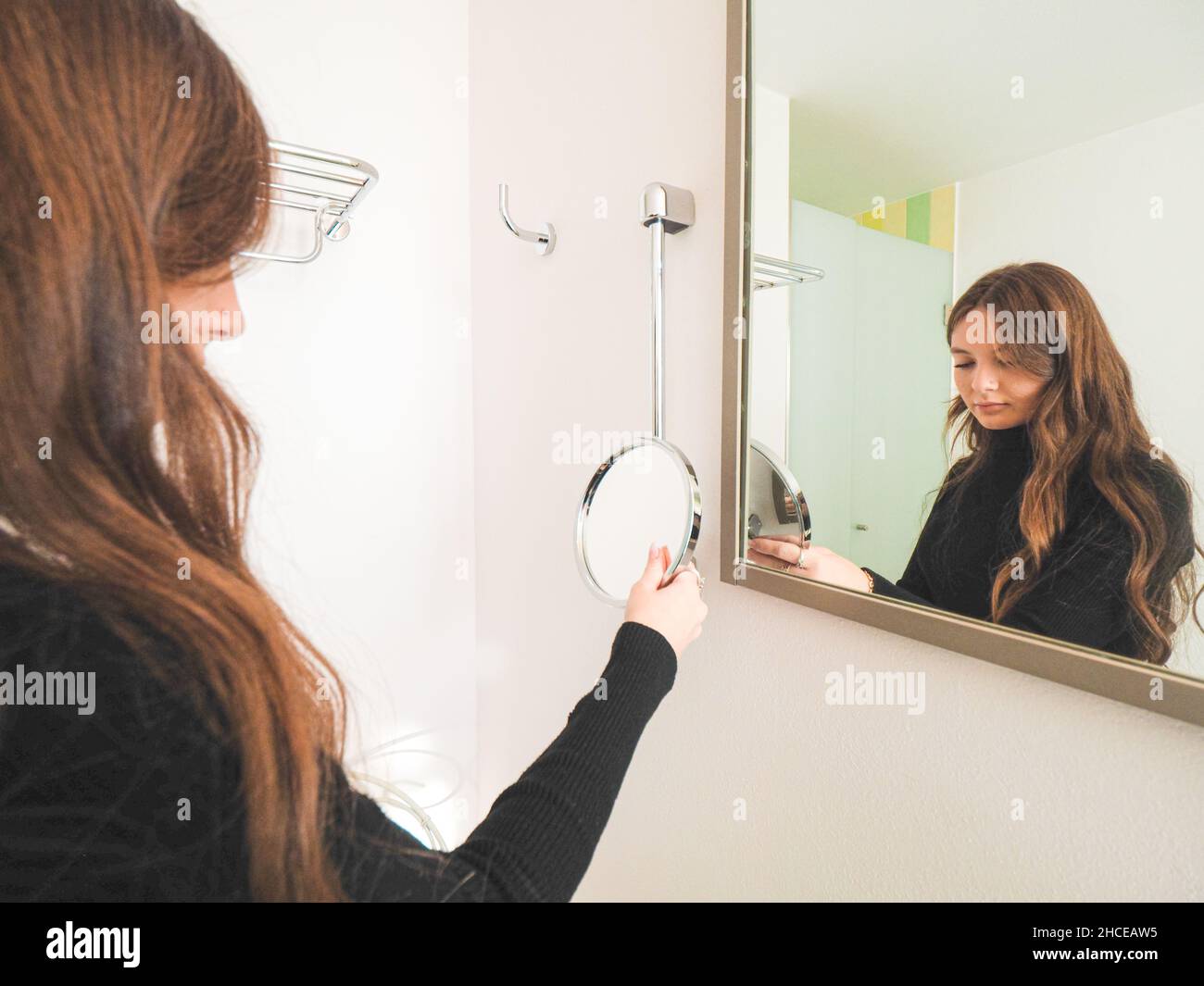 Closeup shot of a beautiful woman looking into the small mirror, in ...