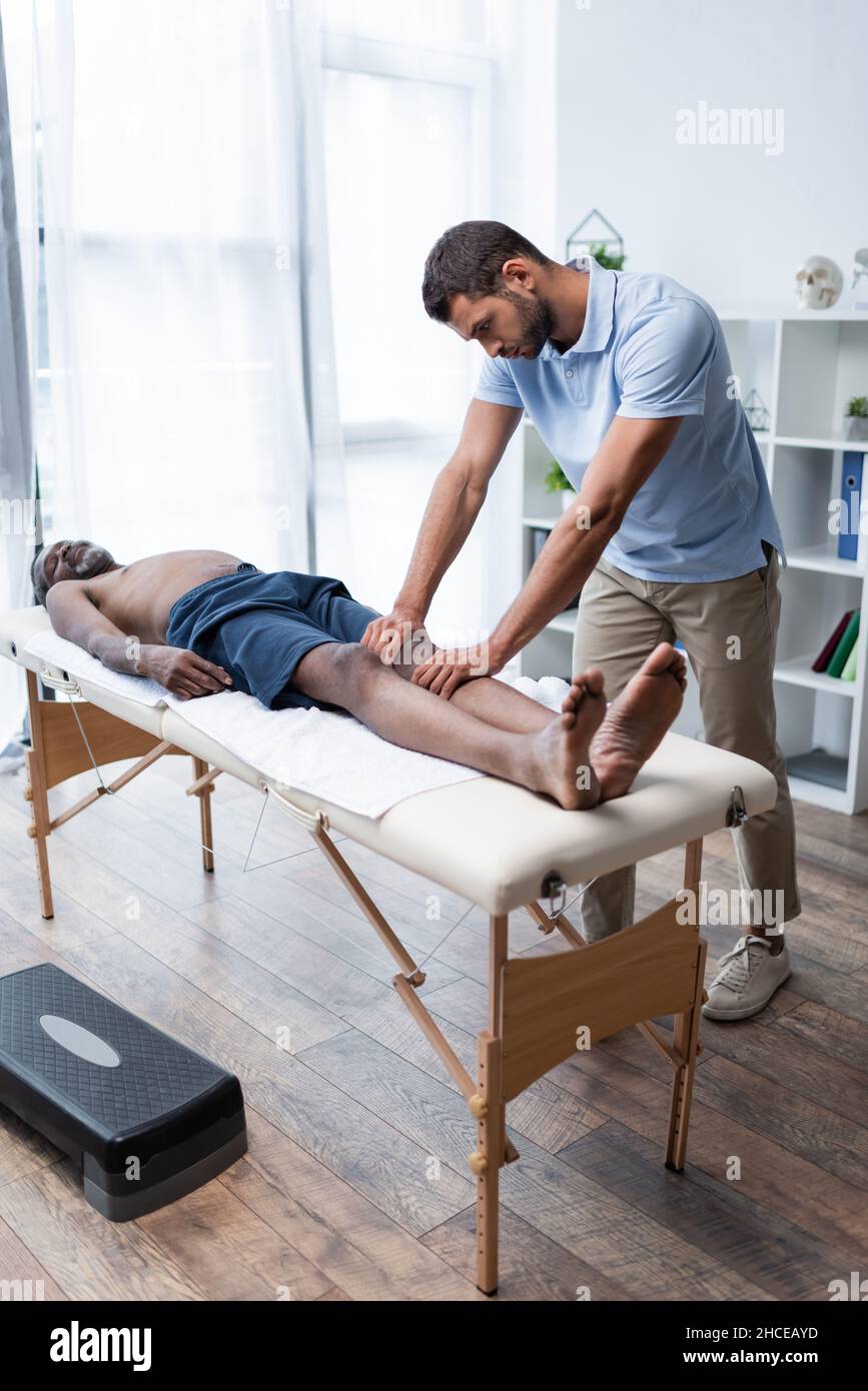 full length view of mature african american man lying on massage table ...