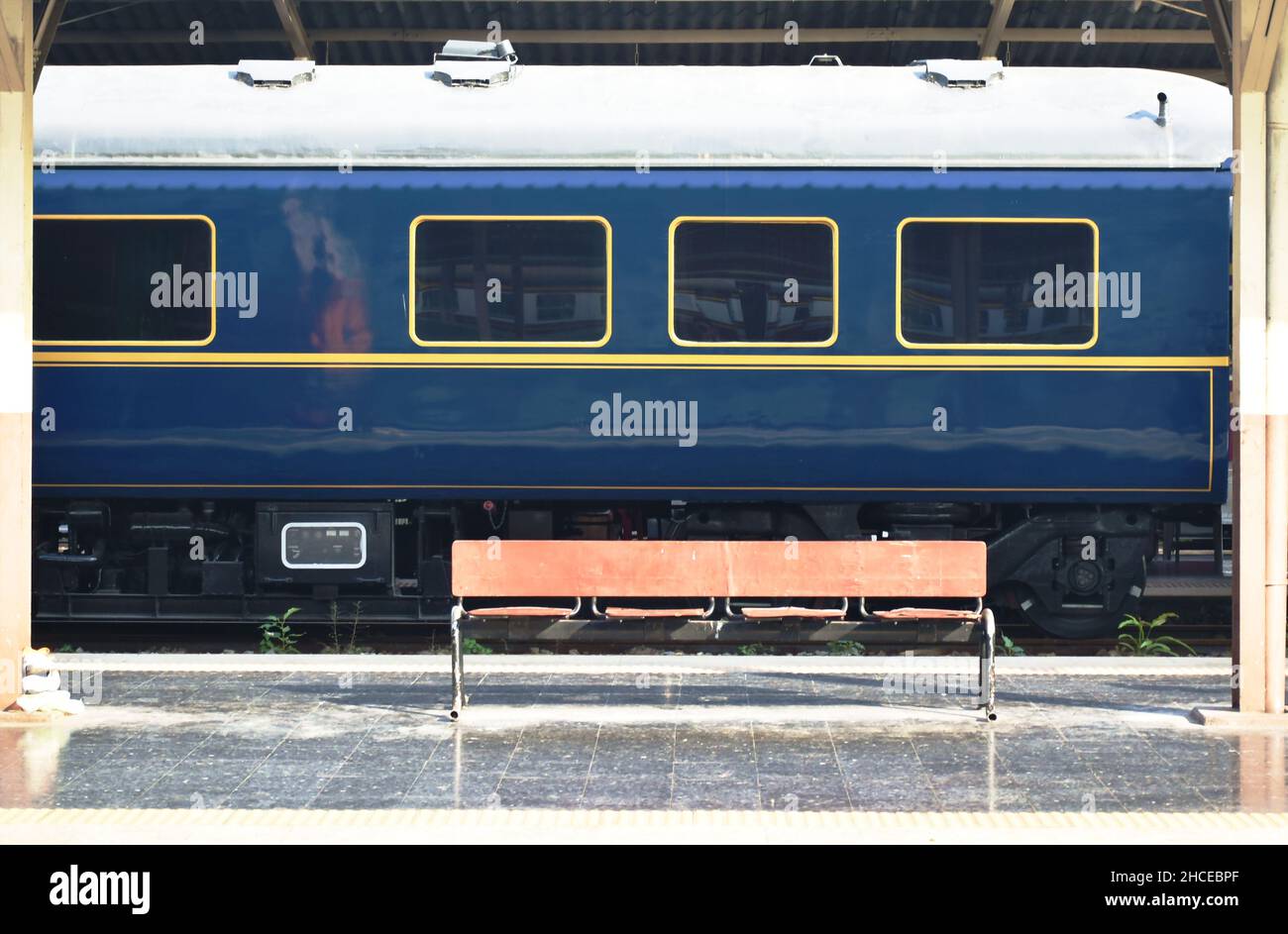 wooden bench for passenger waiting with blue train parking background ...