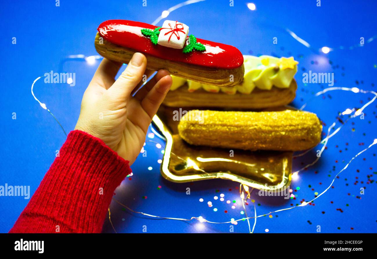 Yummy eclair decorated in New Year theme in hand top view. Christmas ...