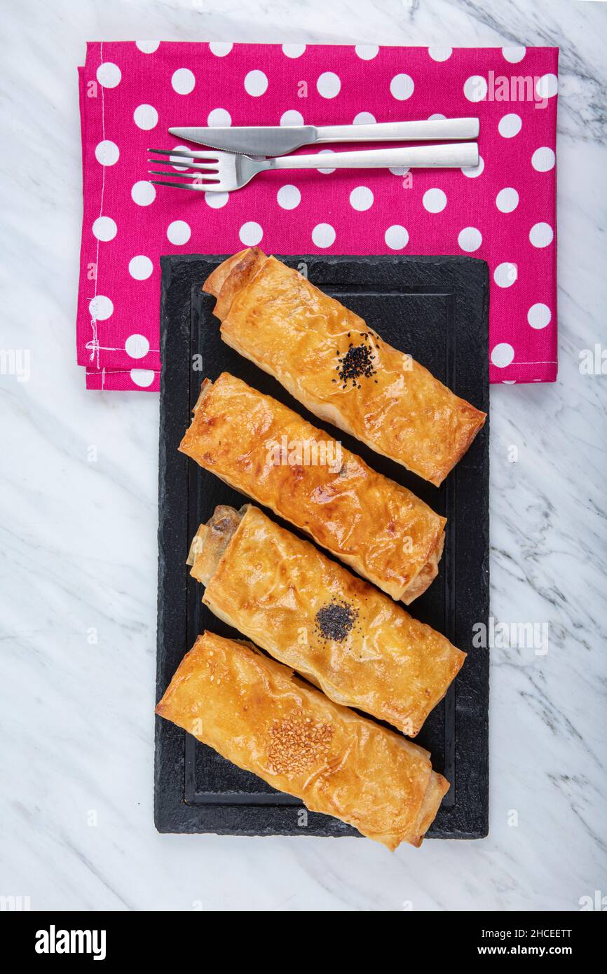 Turkish borek rolls with spinach and cheese on the white plate. A ...