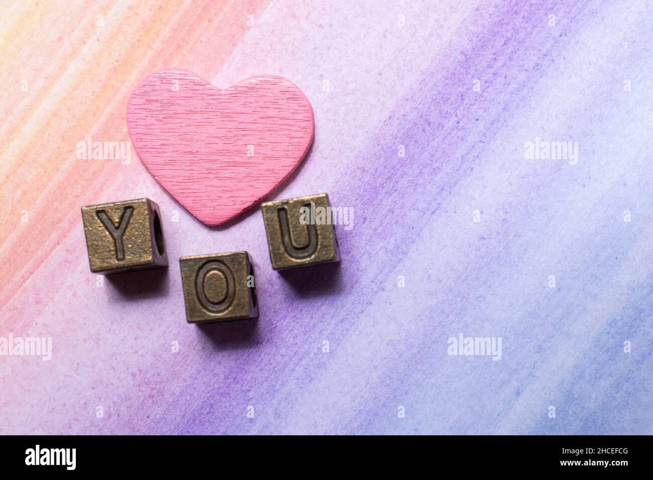 Pink heart and the word YOU composed with cube letters in the colorful ...