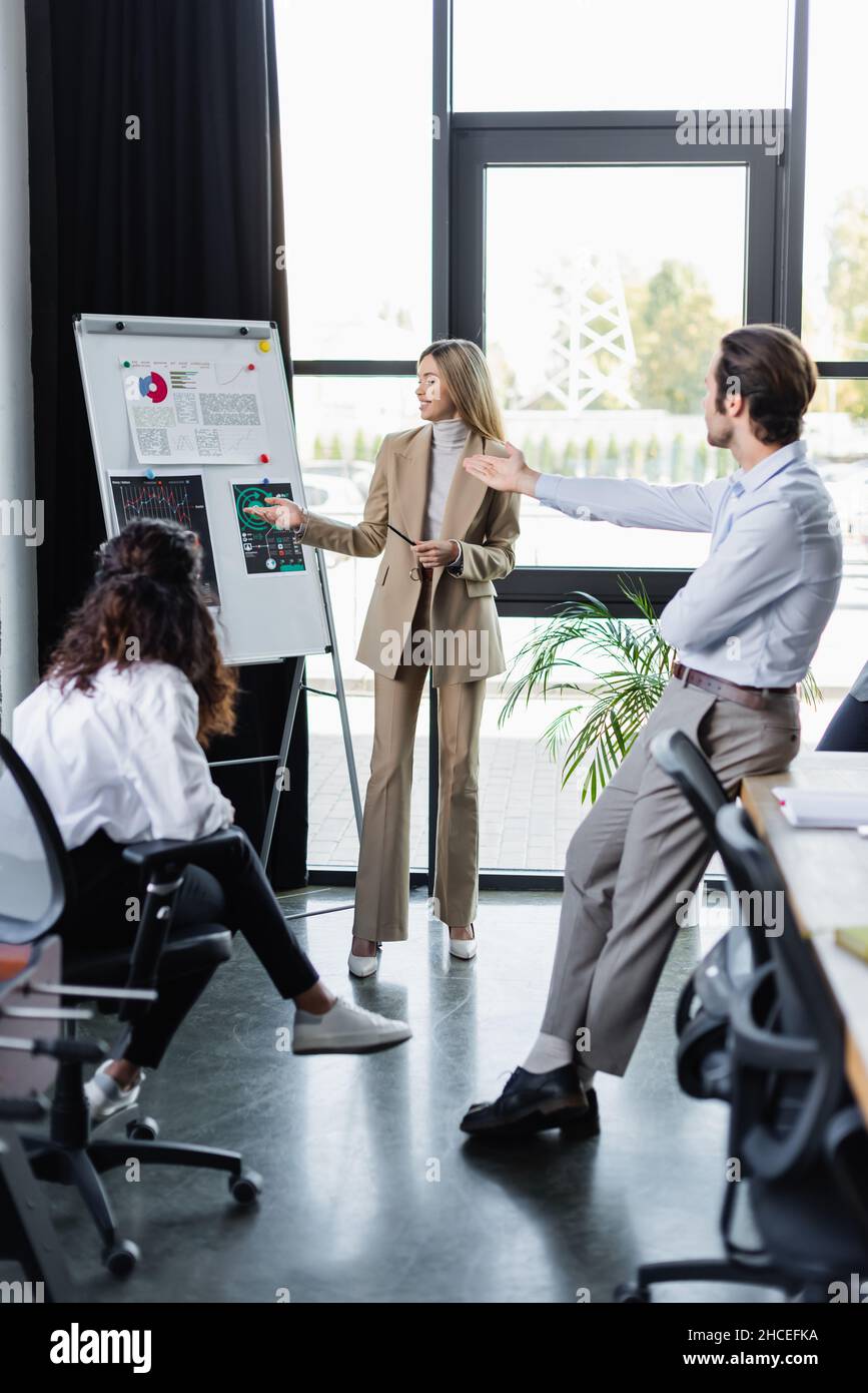business colleagues pointing at flip chart with infographics during ...