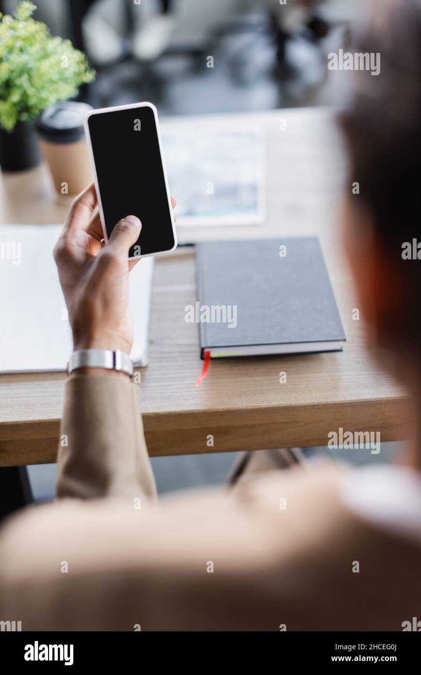 cropped view of blurred african american businessman holding smartphone ...