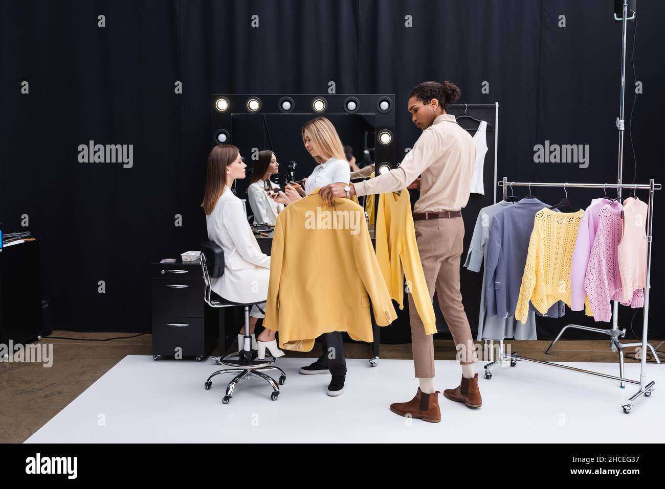 young makeup artist and african american stylist preparing professional ...