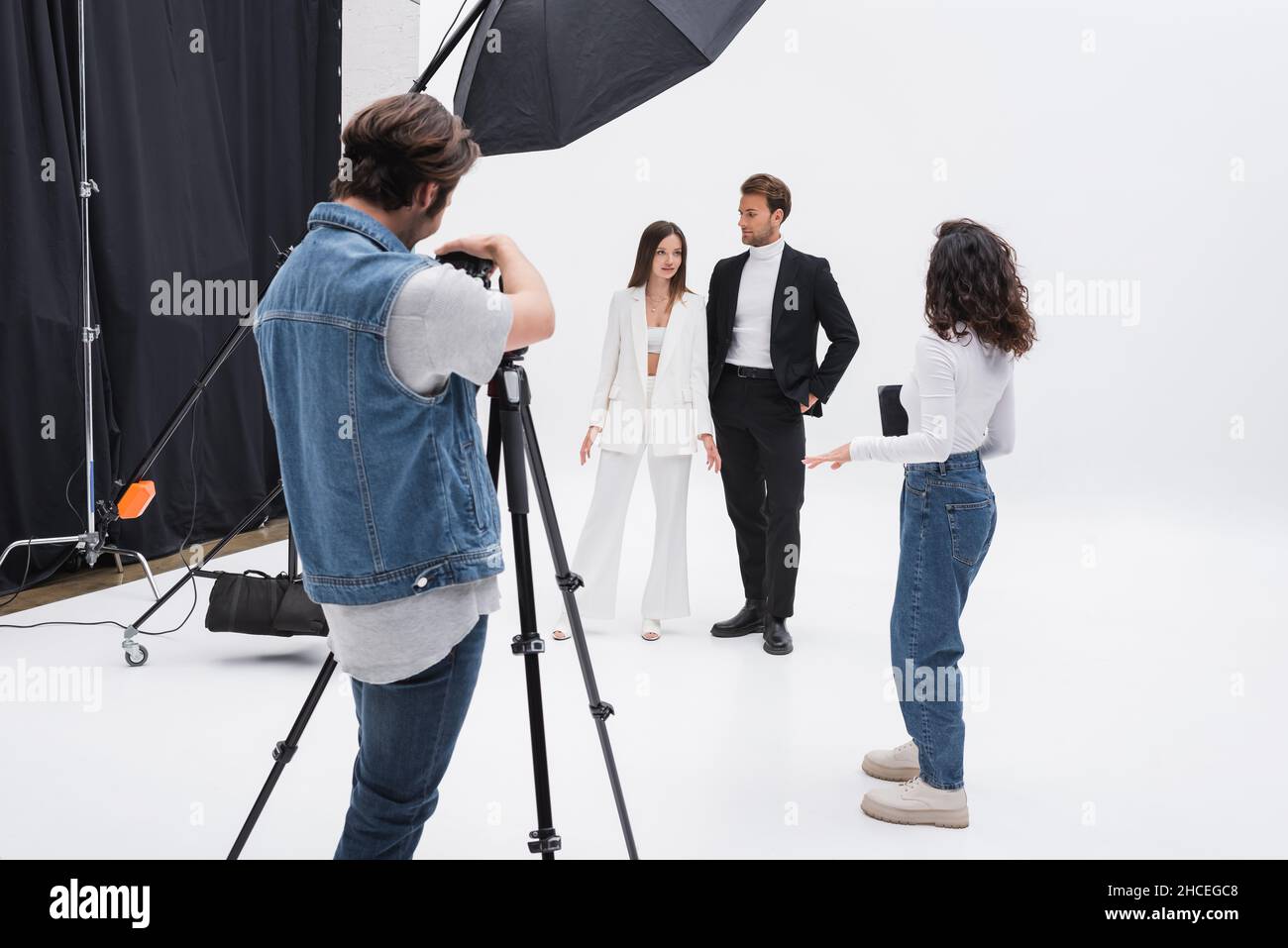 art director talking to models near photographer during photo session ...