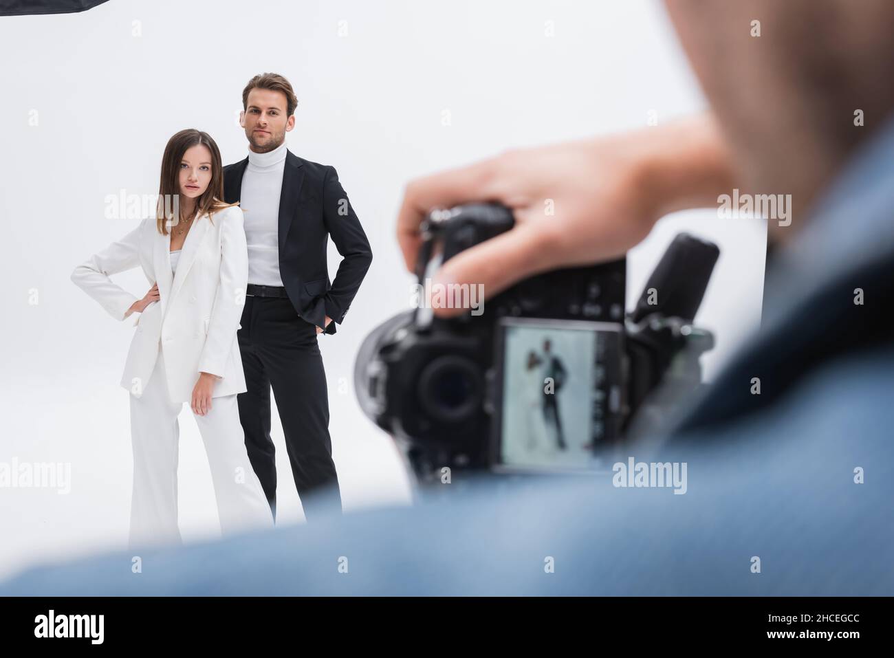 blurred photographer working with young and trendy models posing on ...