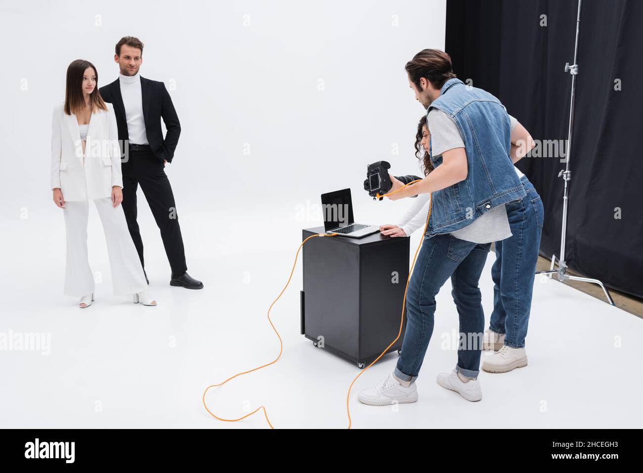 art director with photographer looking at laptop with blank screen near ...