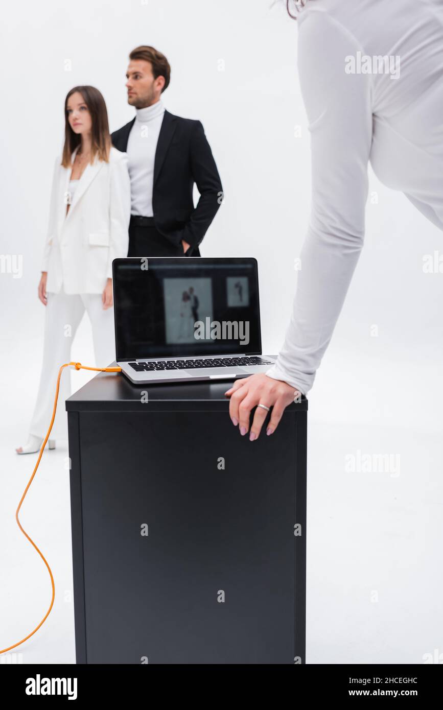 blurred models in suits posing near art director and laptop isolated on ...