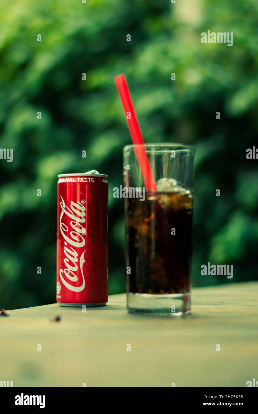Vertical shot of a coca-cola can and a glass with a red straw next to ...