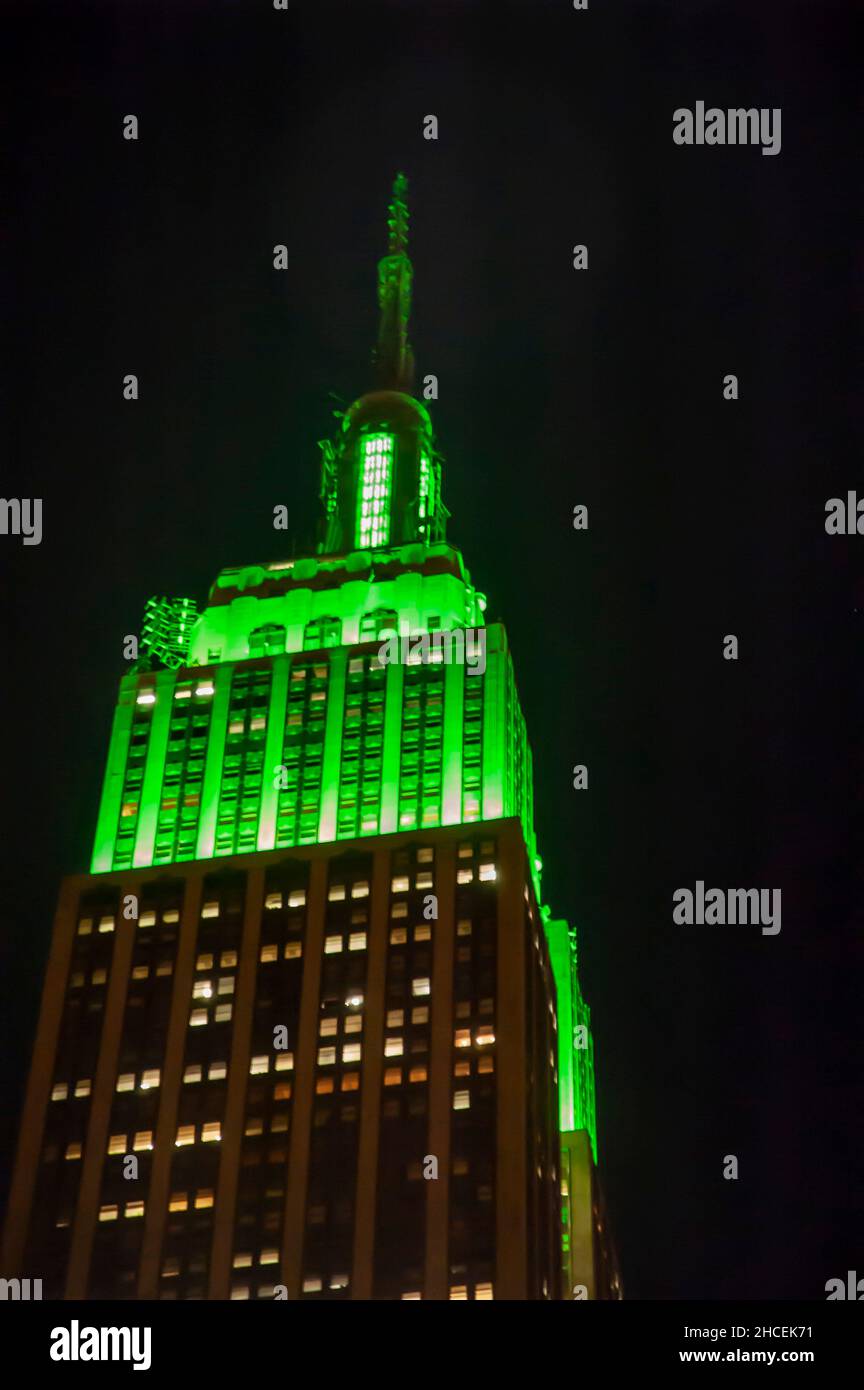 Low angle view of the Empire State Building lit with green light on ...