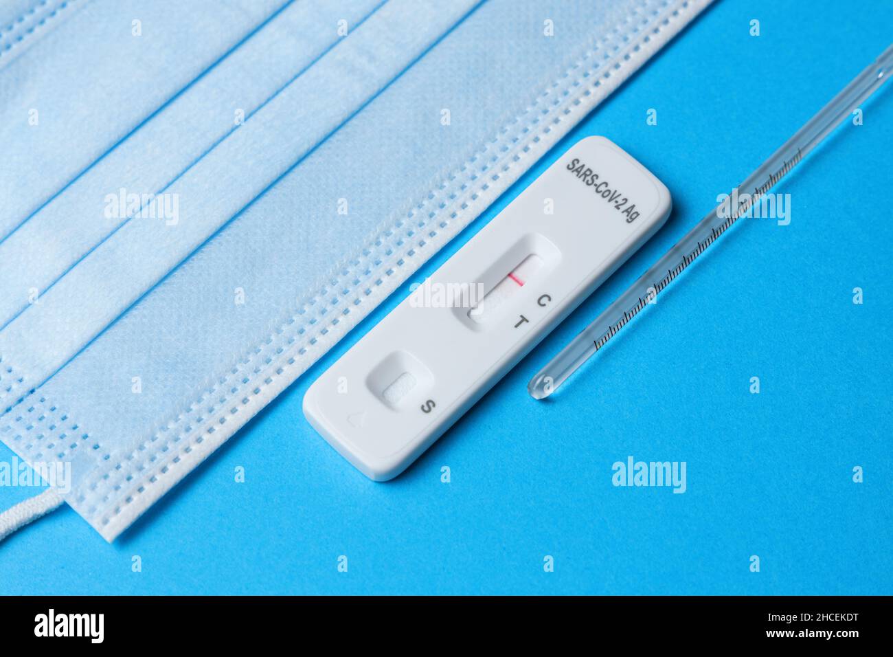 Antigen rapid test, face mask and thermometer on blue background Stock ...