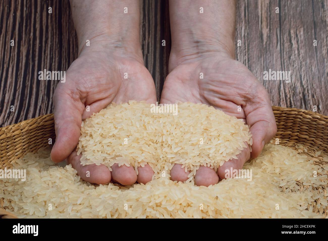Brown bowl full of dry white rice grains. Hands full of fresh white ...