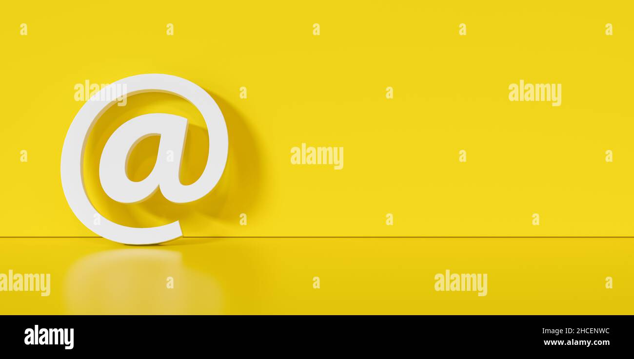 Email Icon or at sign leaning against a yellow wall as a communication ...