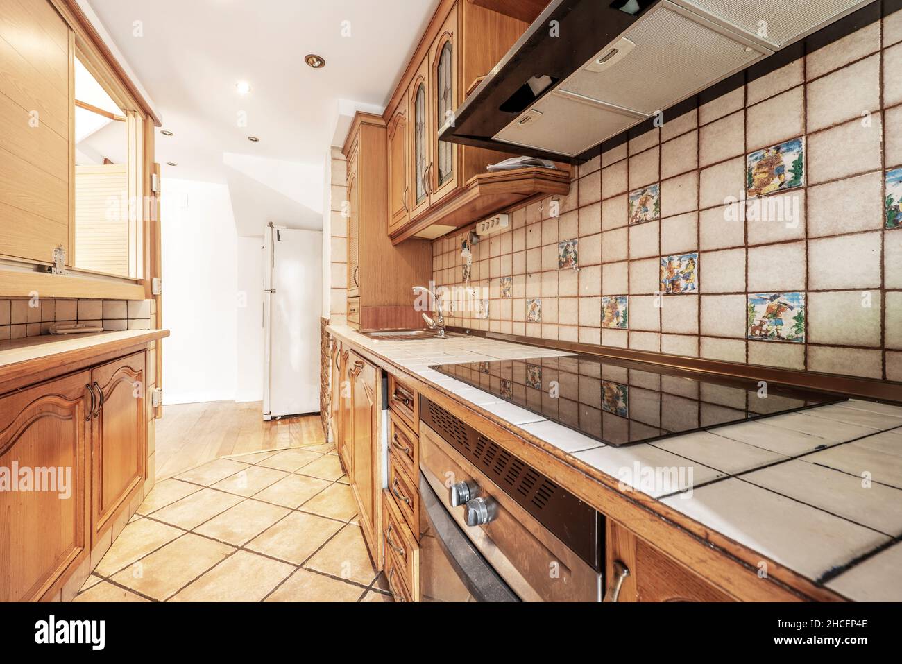 Kitchen with wooden furniture and vintage tiles with black ceramic hob ...