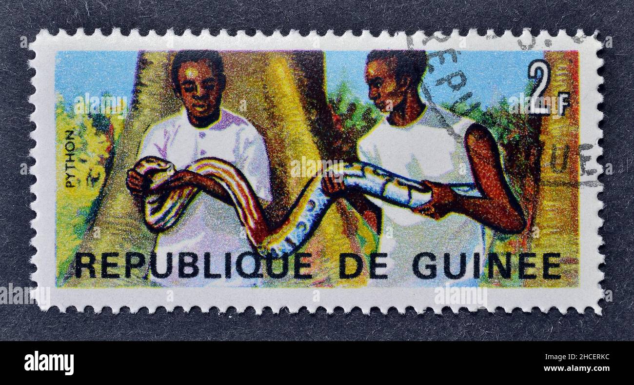 Cancelled postage stamp printed by Guinea, that shows Men Holding Rock ...