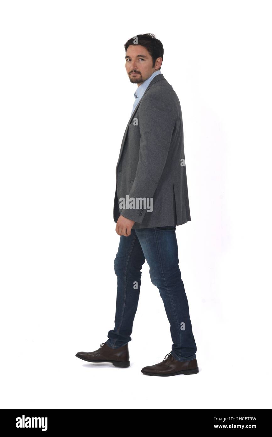 side view of a man with blazer, looking at camera walking on white ...