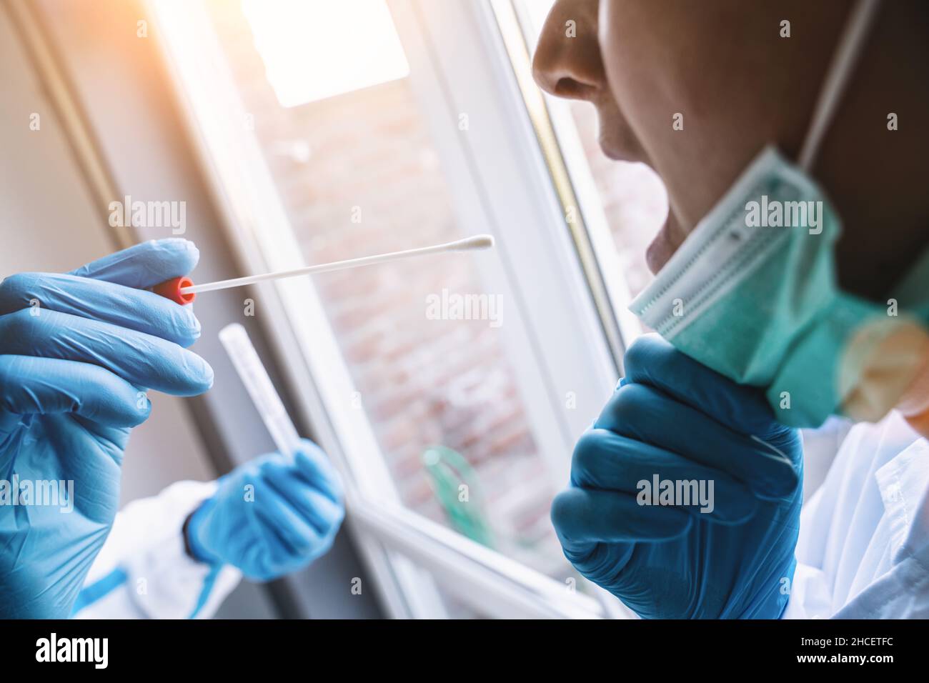 Medical in protective clothing takes COVID-19 swab test tube from mouth ...