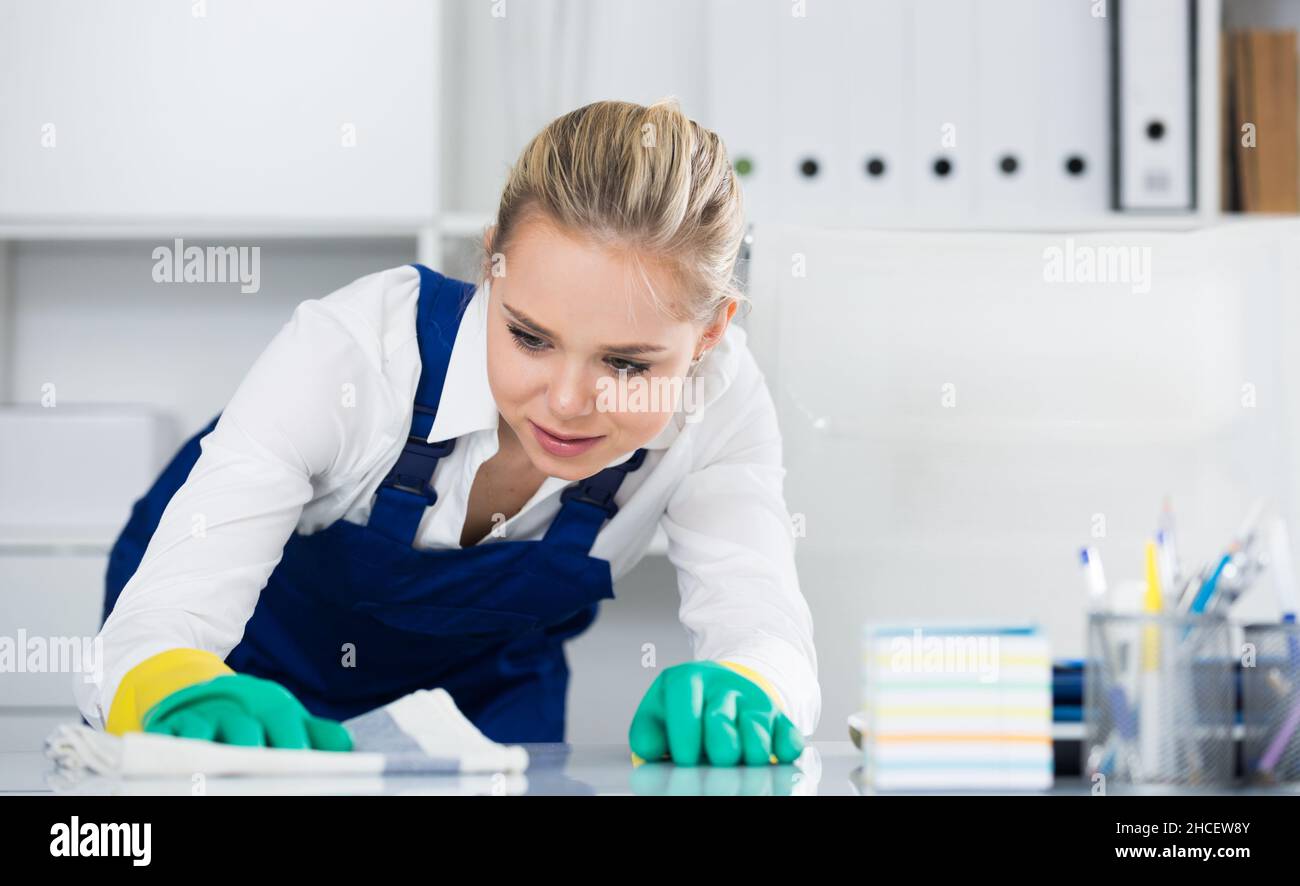 Workwoman wiping dust in office Stock Photo - Alamy