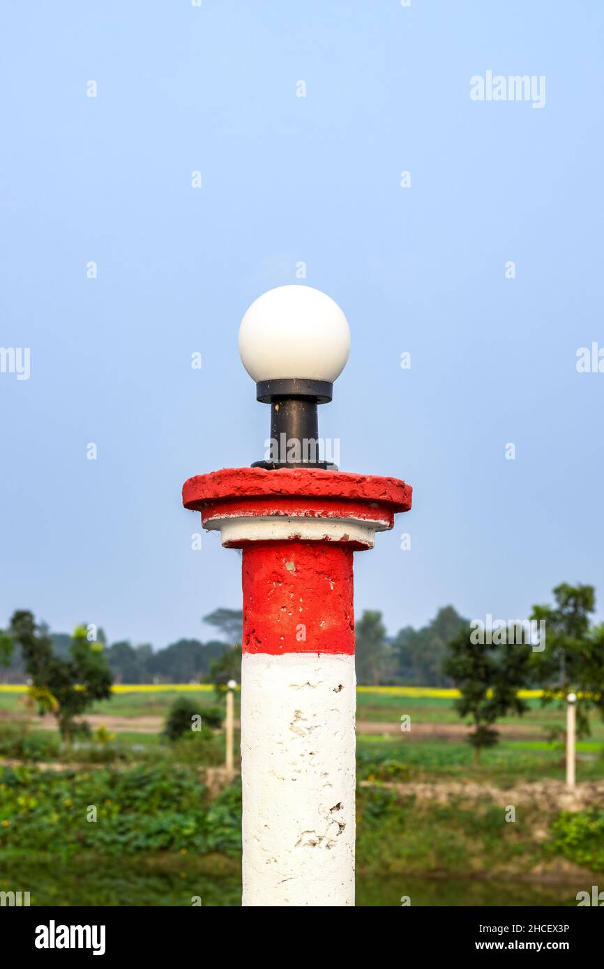 Round white street lamp in the village on a concrete pole under the ...