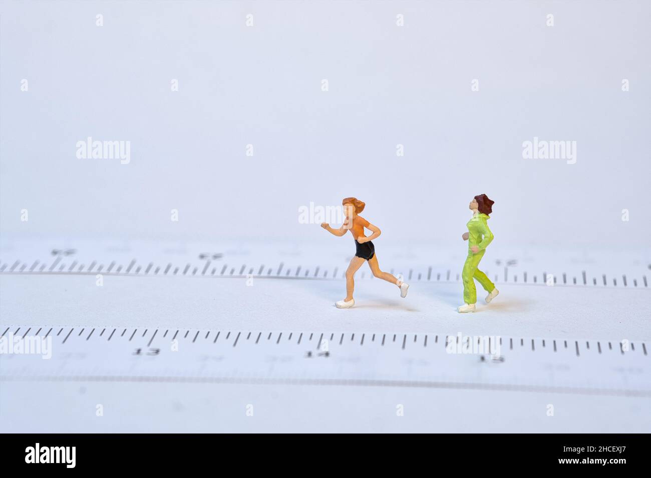 Miniature joggers while running next to a tape measure - white ...