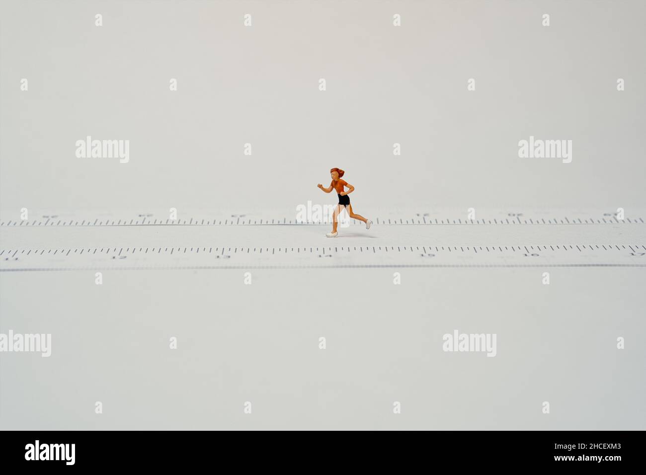 Miniature jogger while running next to a tape measure - white ...