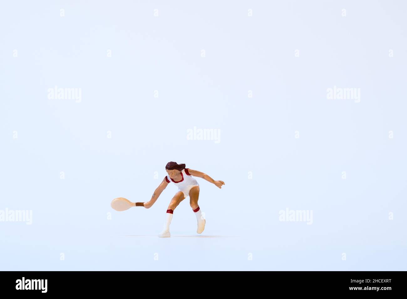 Miniature tennis sportswoman with tennis racket in action position ...