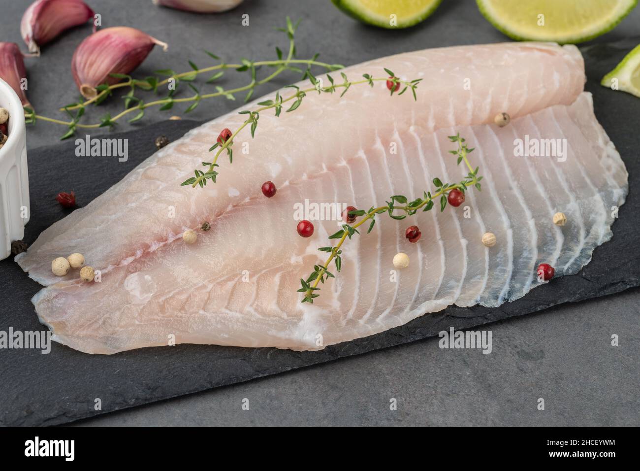 Raw tilapia fish fillet with seasonings over stone background Stock ...