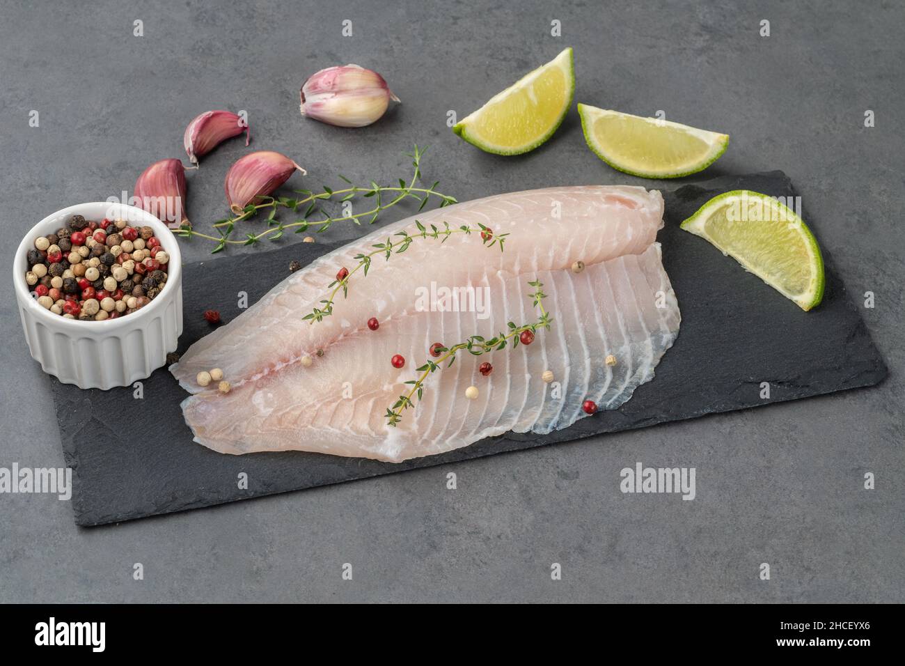 Raw tilapia fish fillet with seasonings over stone background Stock ...