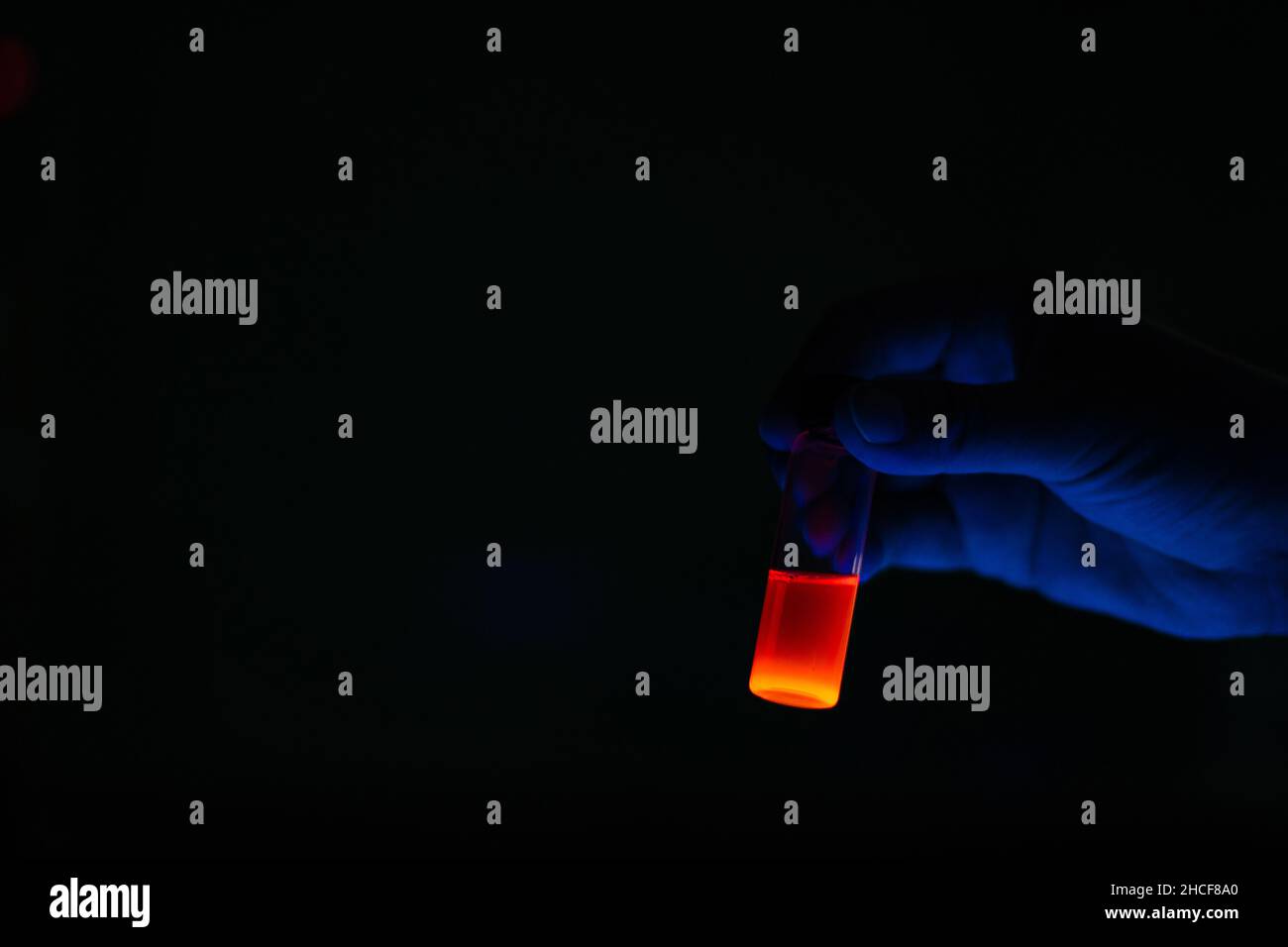 A woman researcher holding chemistry photochemical reaction fluorescent ...