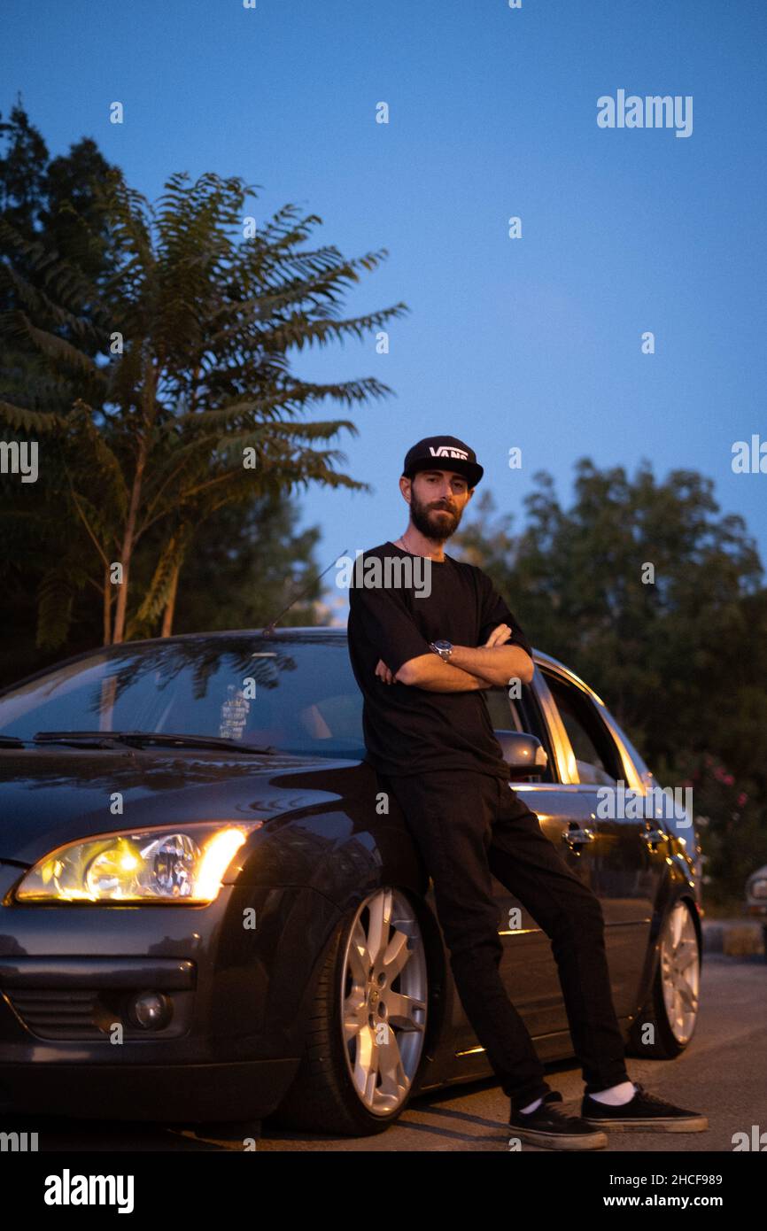 Man sitting on his car while posing for a camera Stock Photo - Alamy