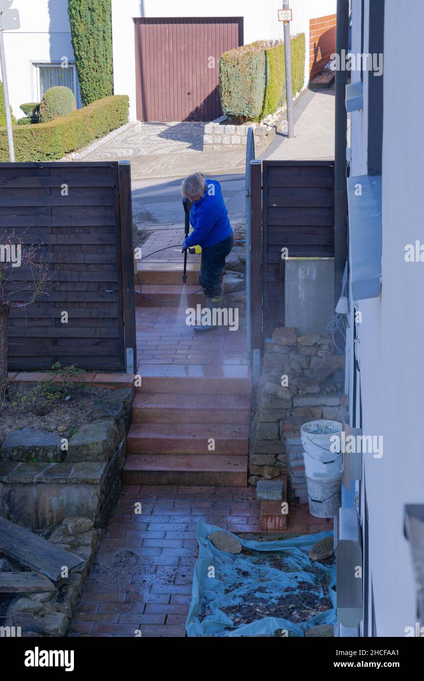 Worker cleaning driveway with gasoline high pressure washer splashing ...