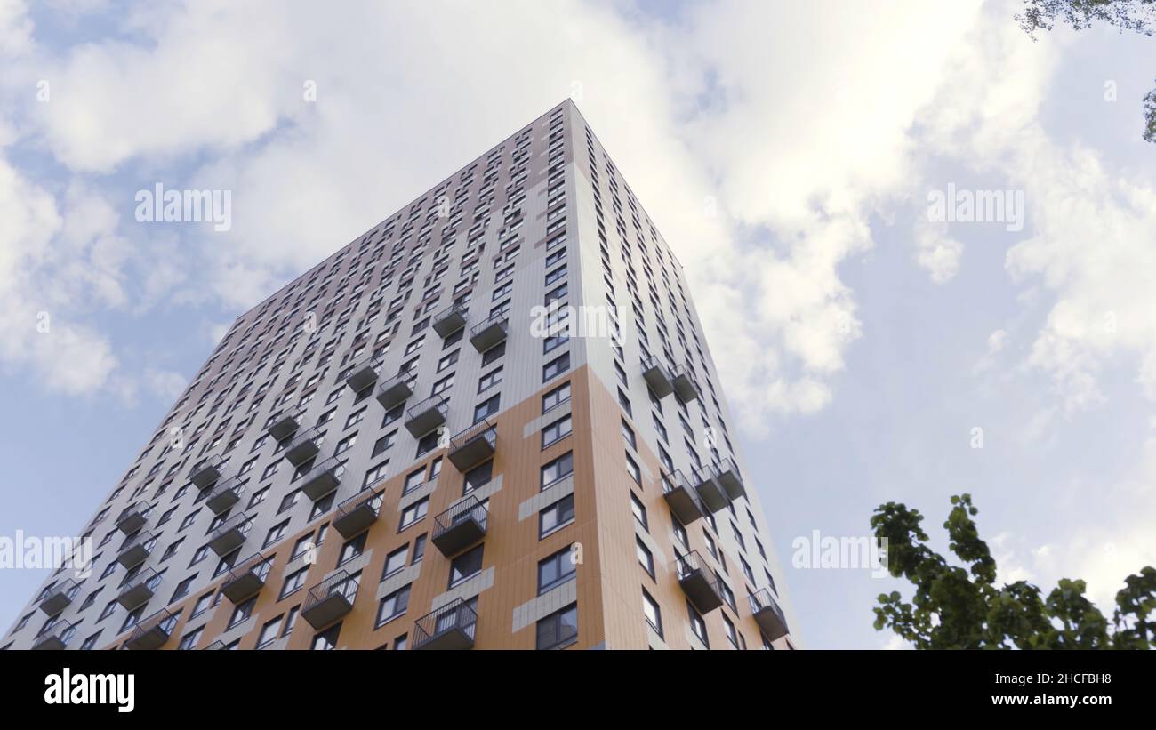 Bottom view of an apartment building on blue cloudy sky background. New ...