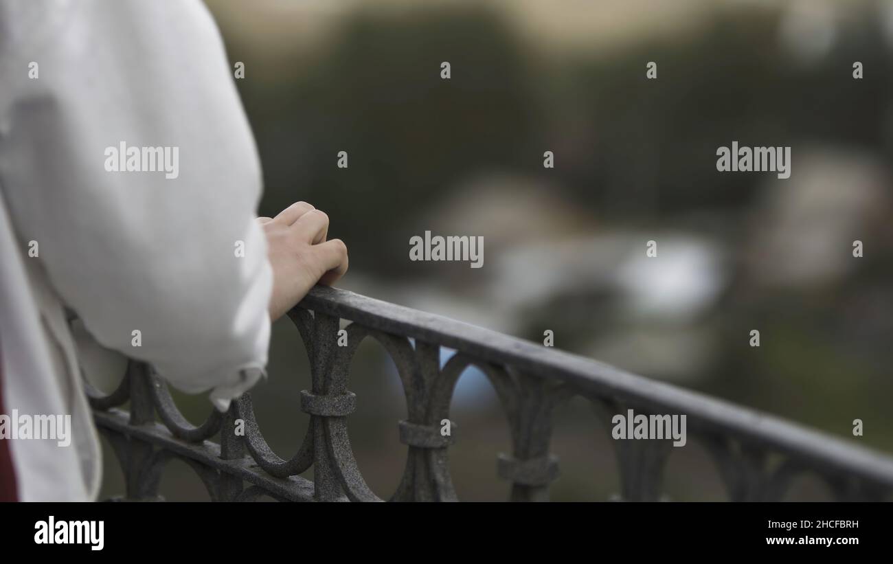 Rear view of a woman in white clothes at the balcony. Close up of ...