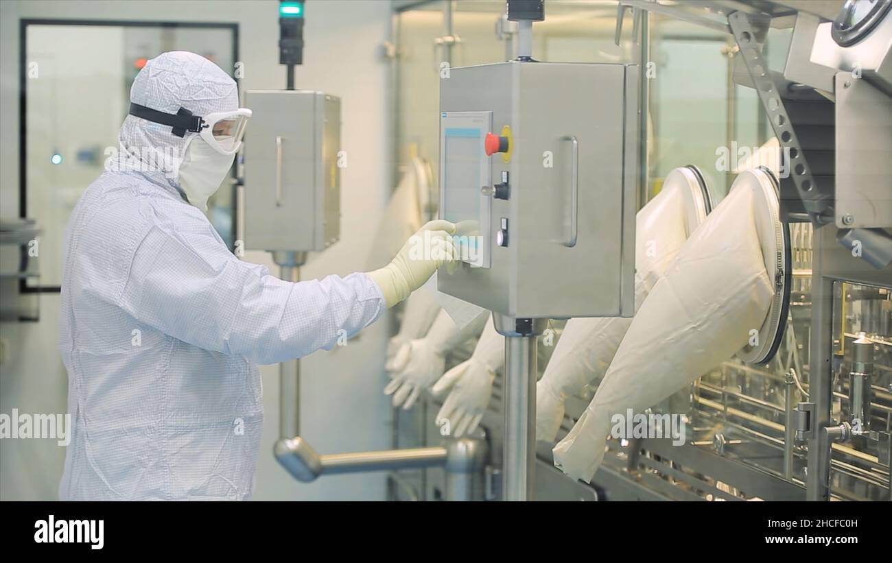 Worker at pharmaceutical factory operating control panel of the ...
