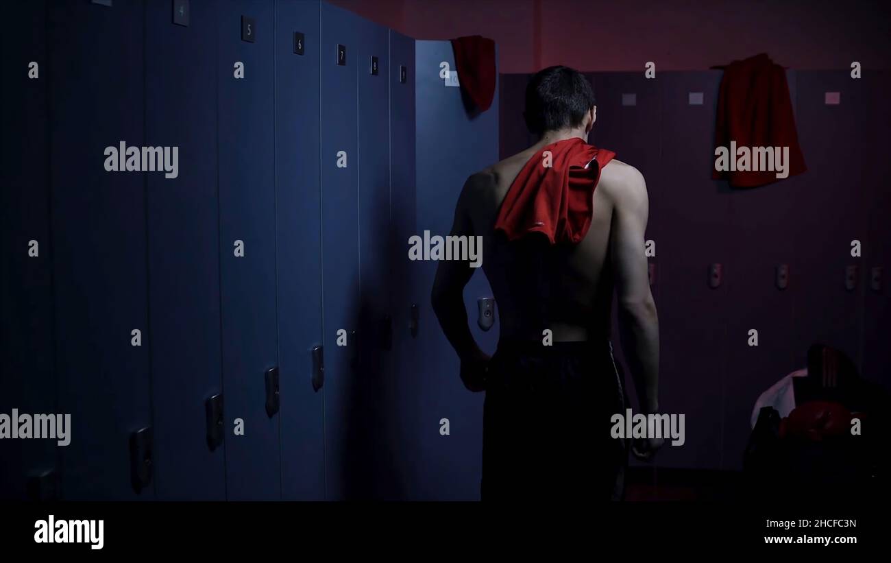 Rear view of an angry sportsman in the changing room slamming the door ...
