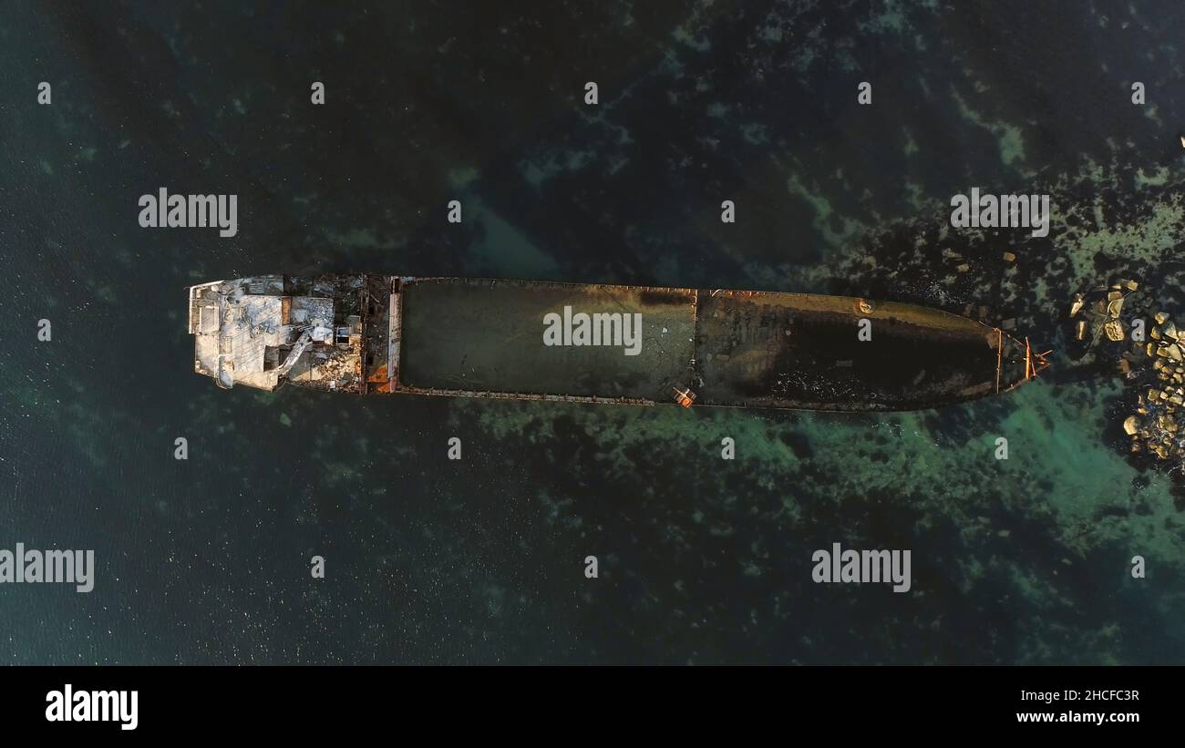 Aerial top view for wrecked ship along the rocky coast in blue water ...