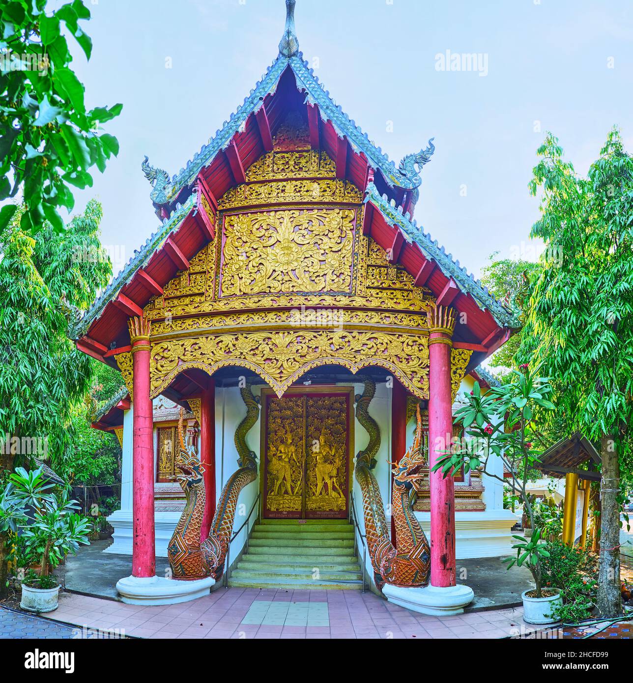 The carved wooden facade of the Viharn with pillars, carvings, gilt ...