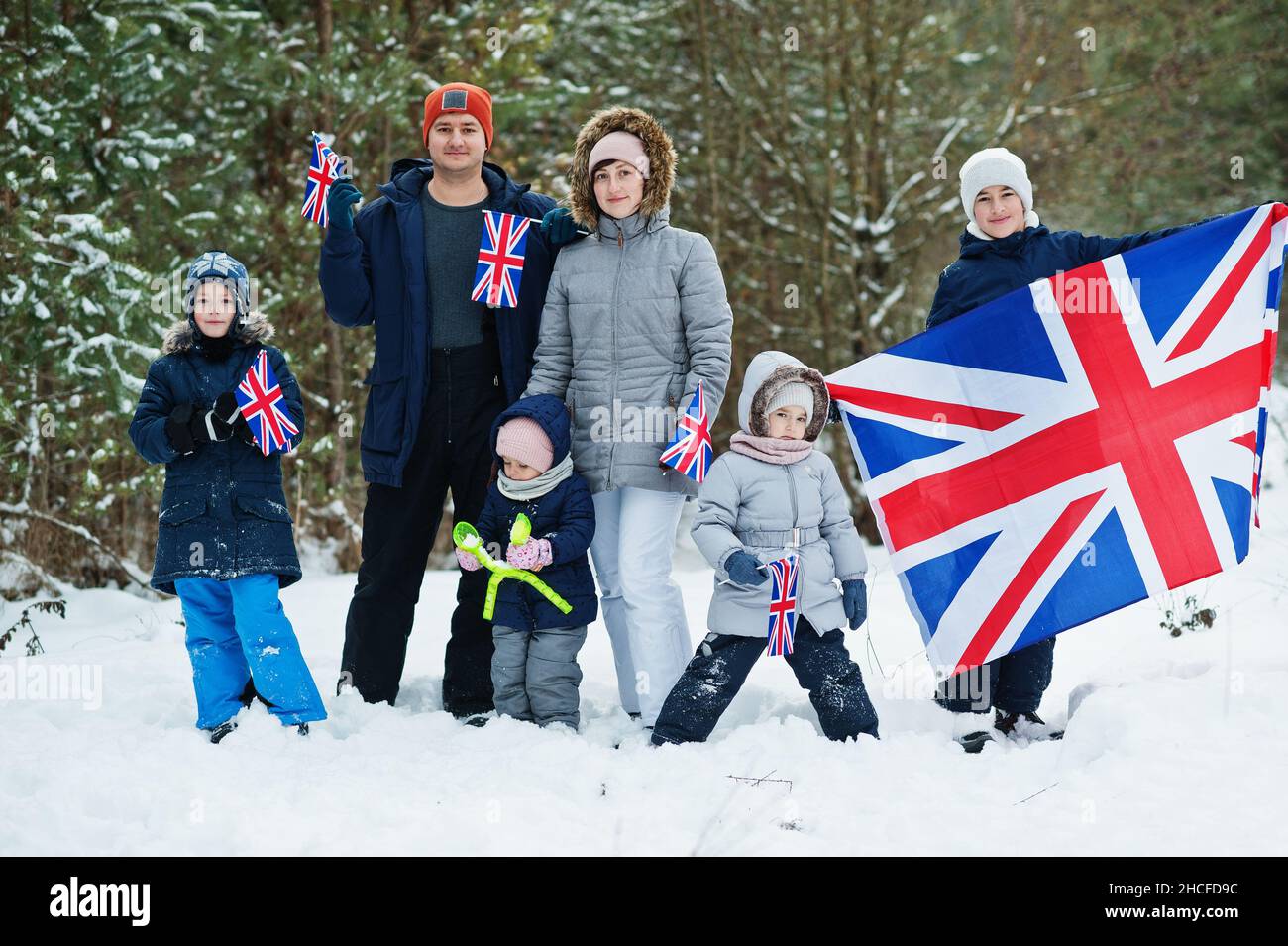 Family with four kids holding flag of Great Britain on winter landscape ...