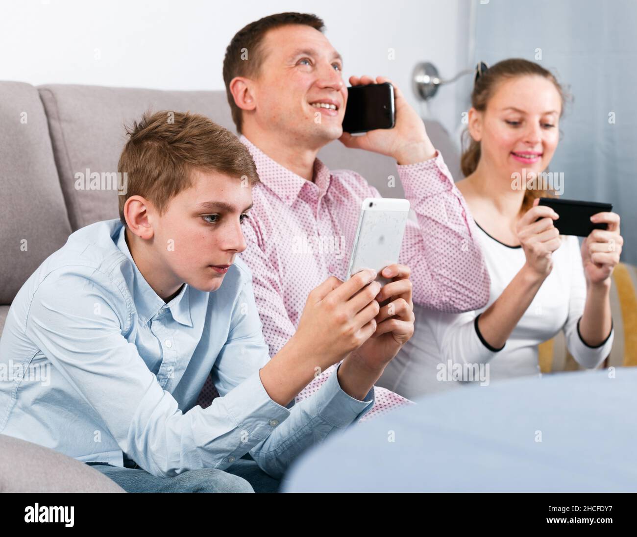 Parents and son using phones Stock Photo - Alamy