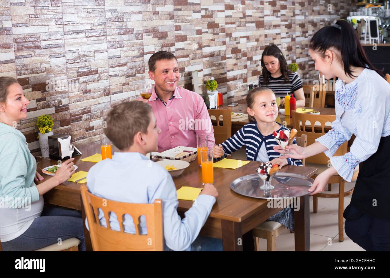Waitress is bringing delicious dessert to young visitors Stock Photo ...
