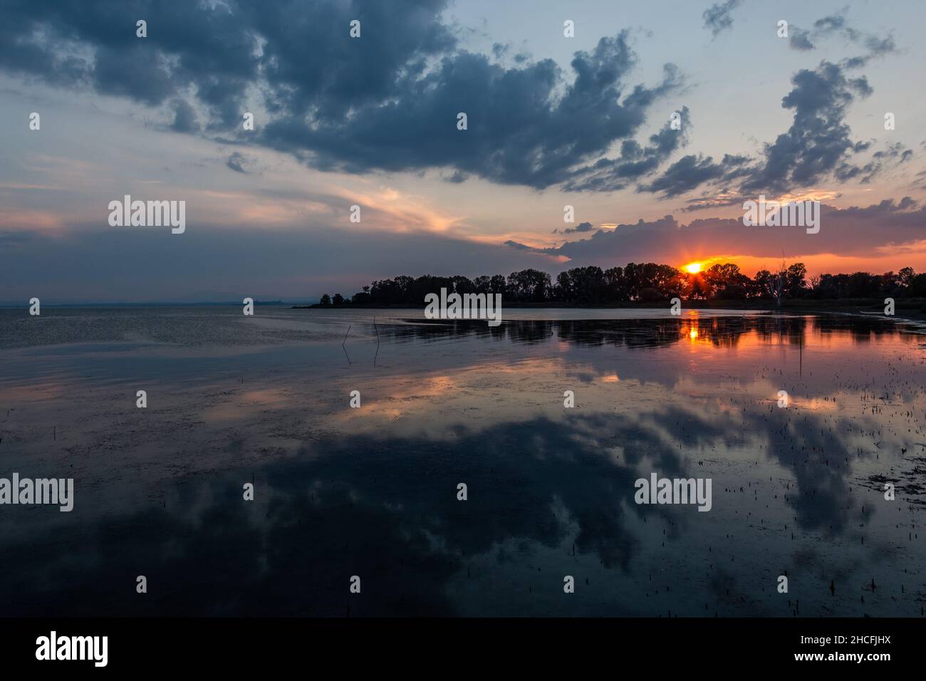 Perfectly symmetric clouds and trees reflections on a lake at sunset ...