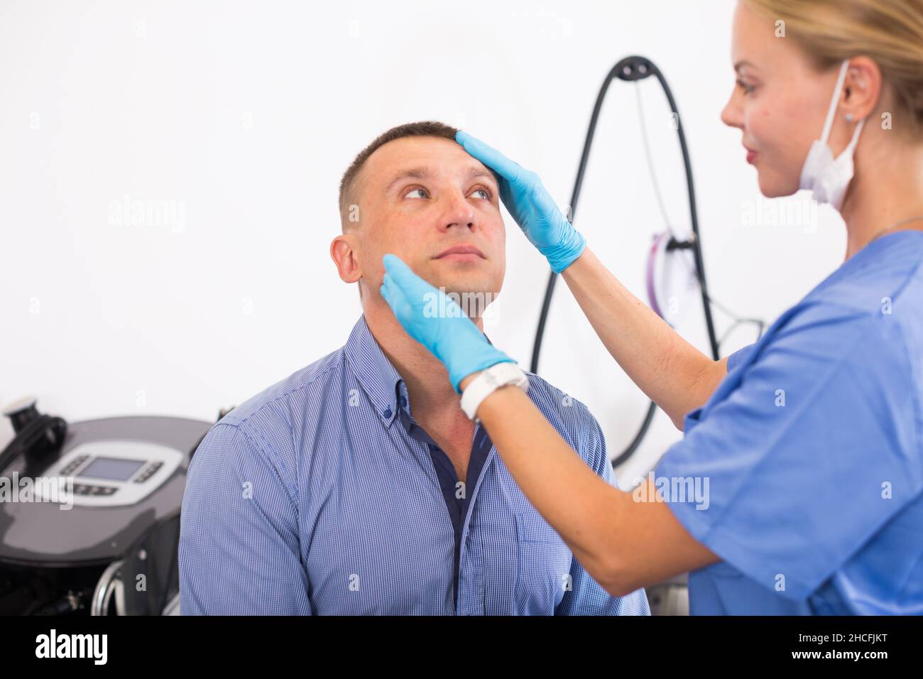 Female doctor is examining face of client after procedure Stock Photo ...