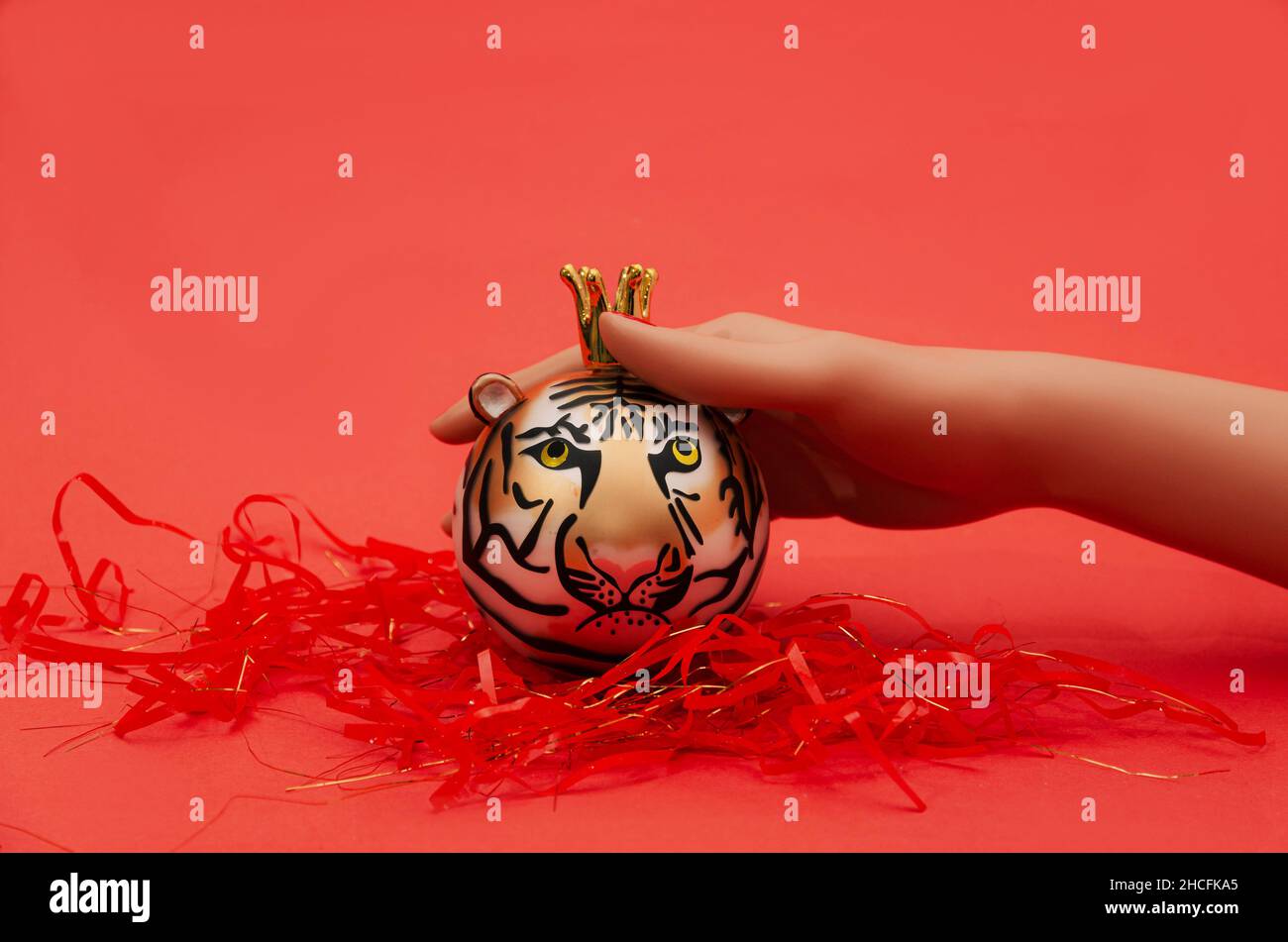A women's hand peting a decoration in the shape of a tiger on bright ...