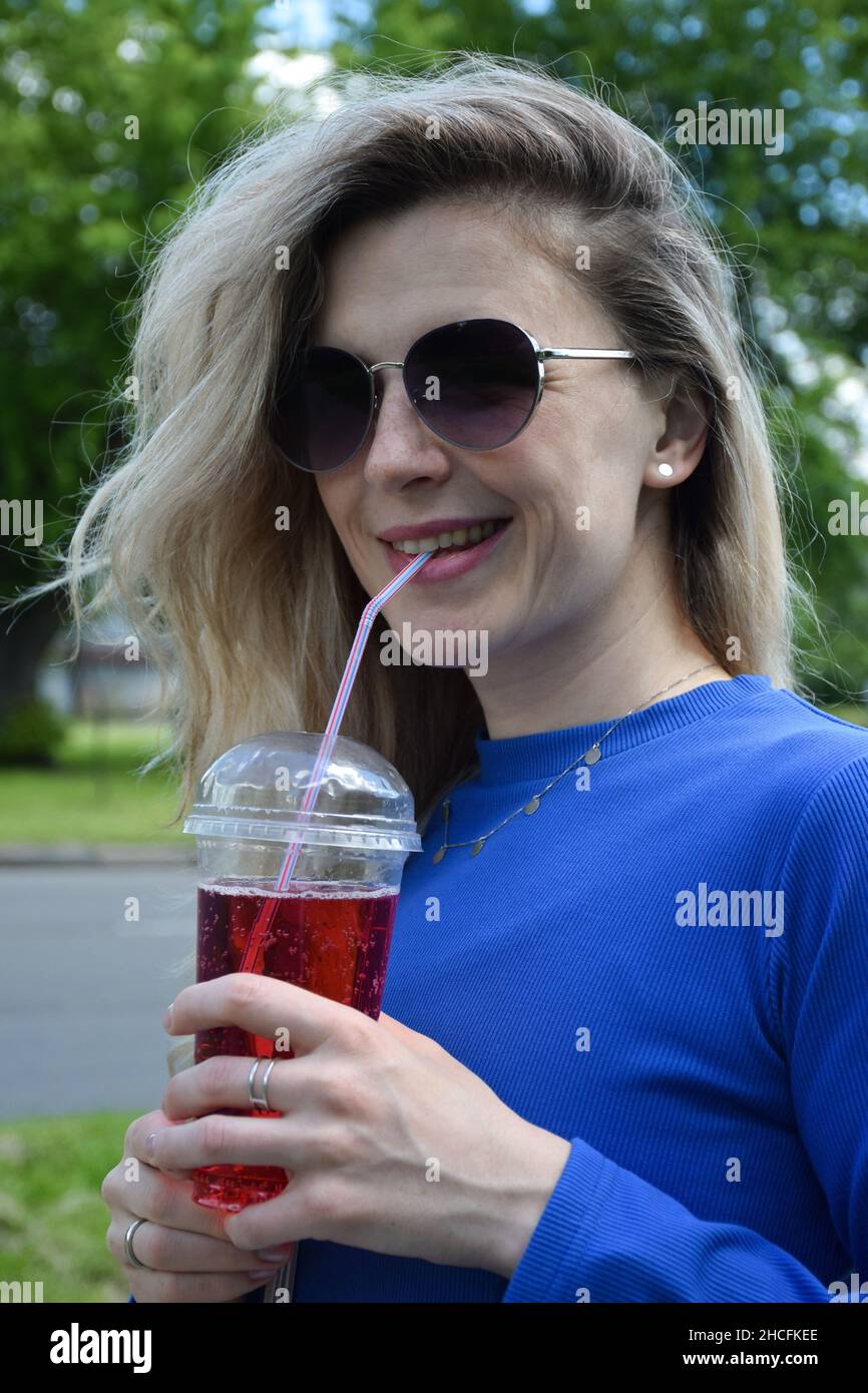 Attractive blonde girl in sunglasses drinks an effervescent cocktail ...