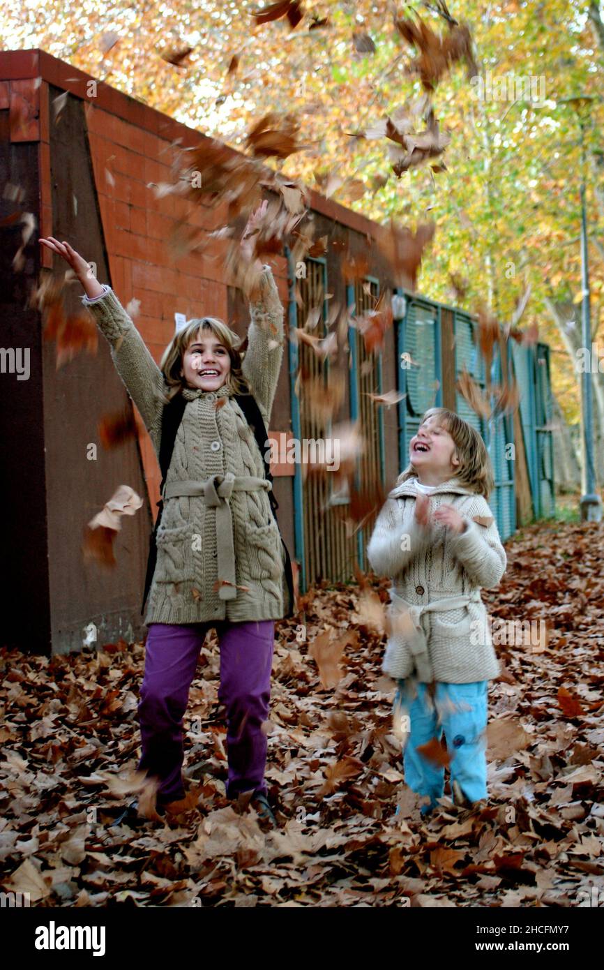 Two girls playing with leaves Stock Photo - Alamy