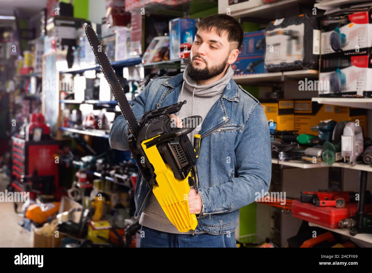 Positive consumer chooses chainsaw in a tool store Stock Photo - Alamy