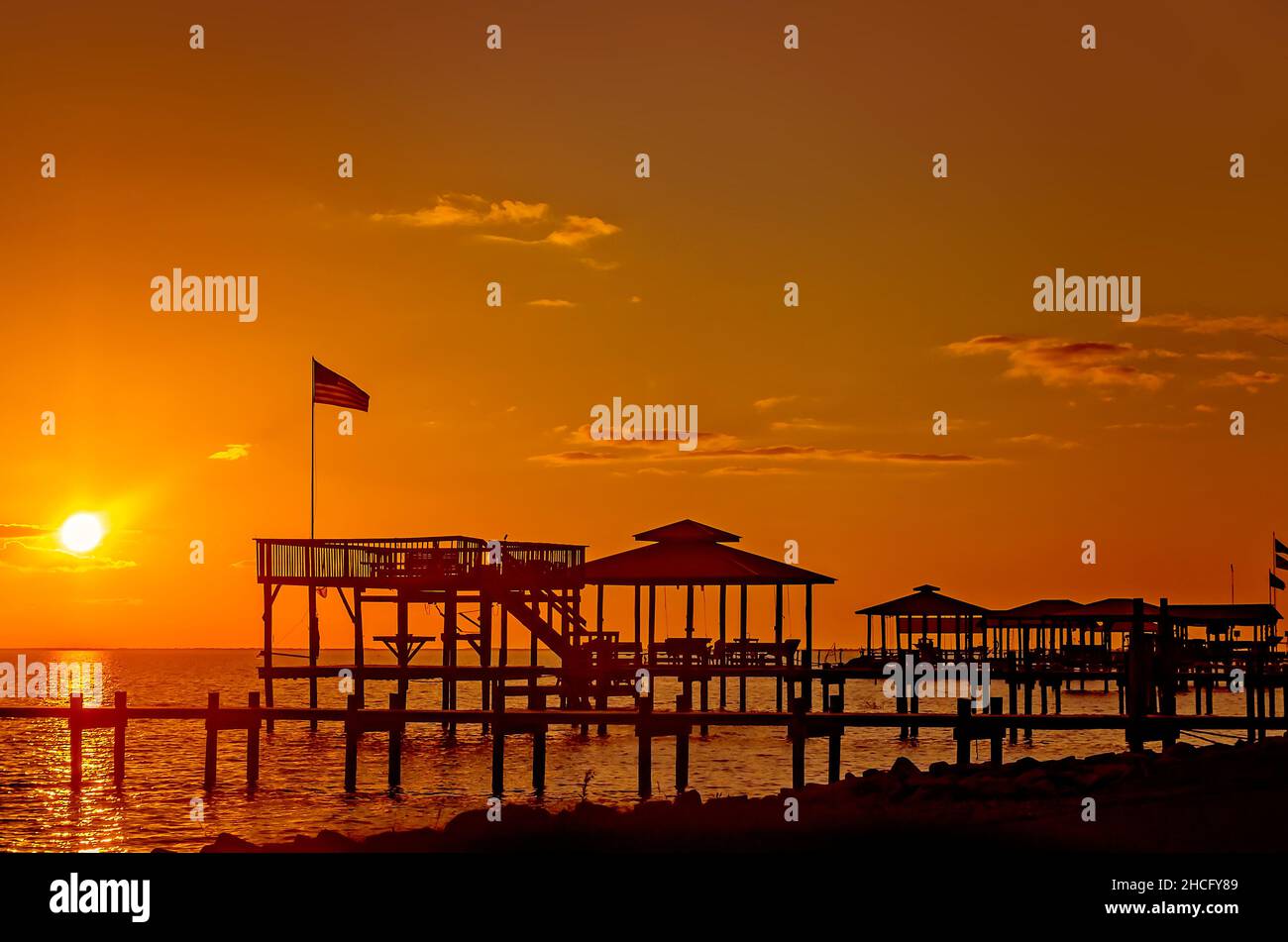 The sun sets behind boat docks and fishing piers on Coden Beach, Dec ...
